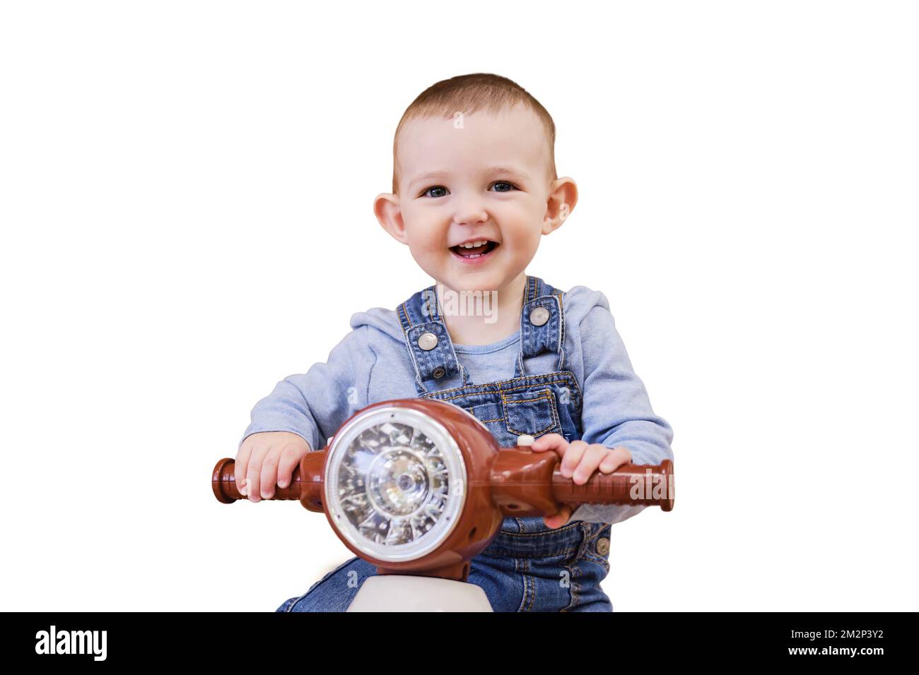 Happy baby boy rides a plastic children motorcycle in the playroom ...