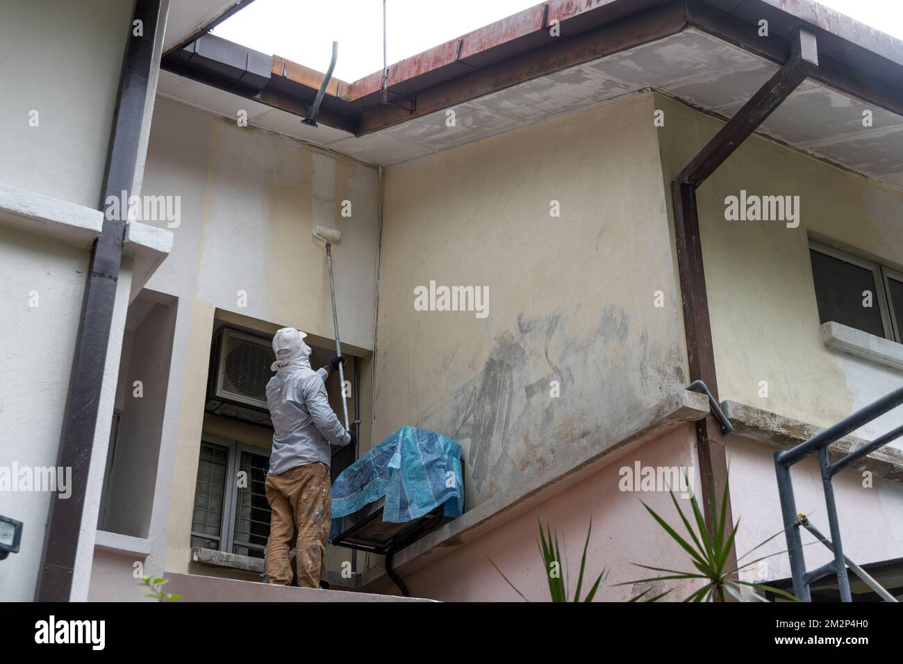Painter worker adding undercoat foundation paint onto wall with roller ...