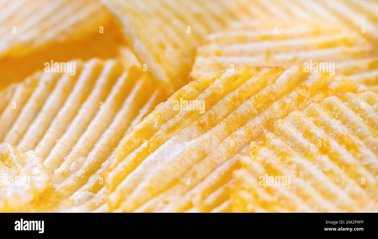 Yellow crispy ridged potato chips close up. Food background, banner ...