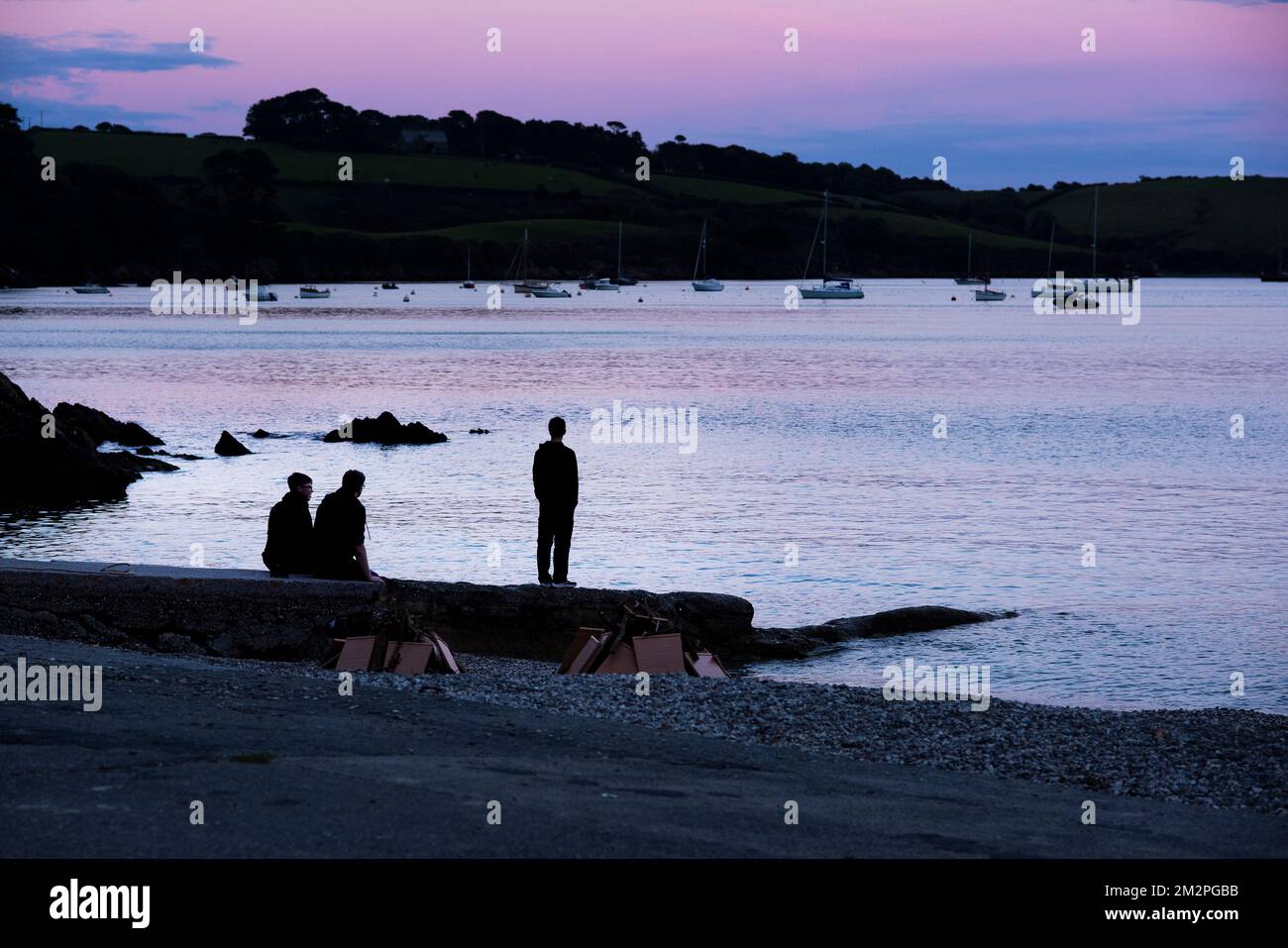 Evening light silhouetting three people on the beach at Polgwidden Cove ...