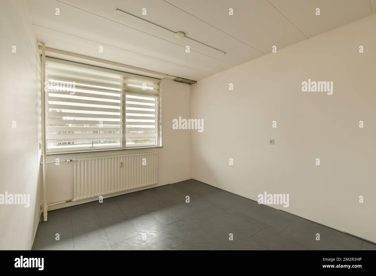 an empty room with white walls and black tile on the floor there is a ...