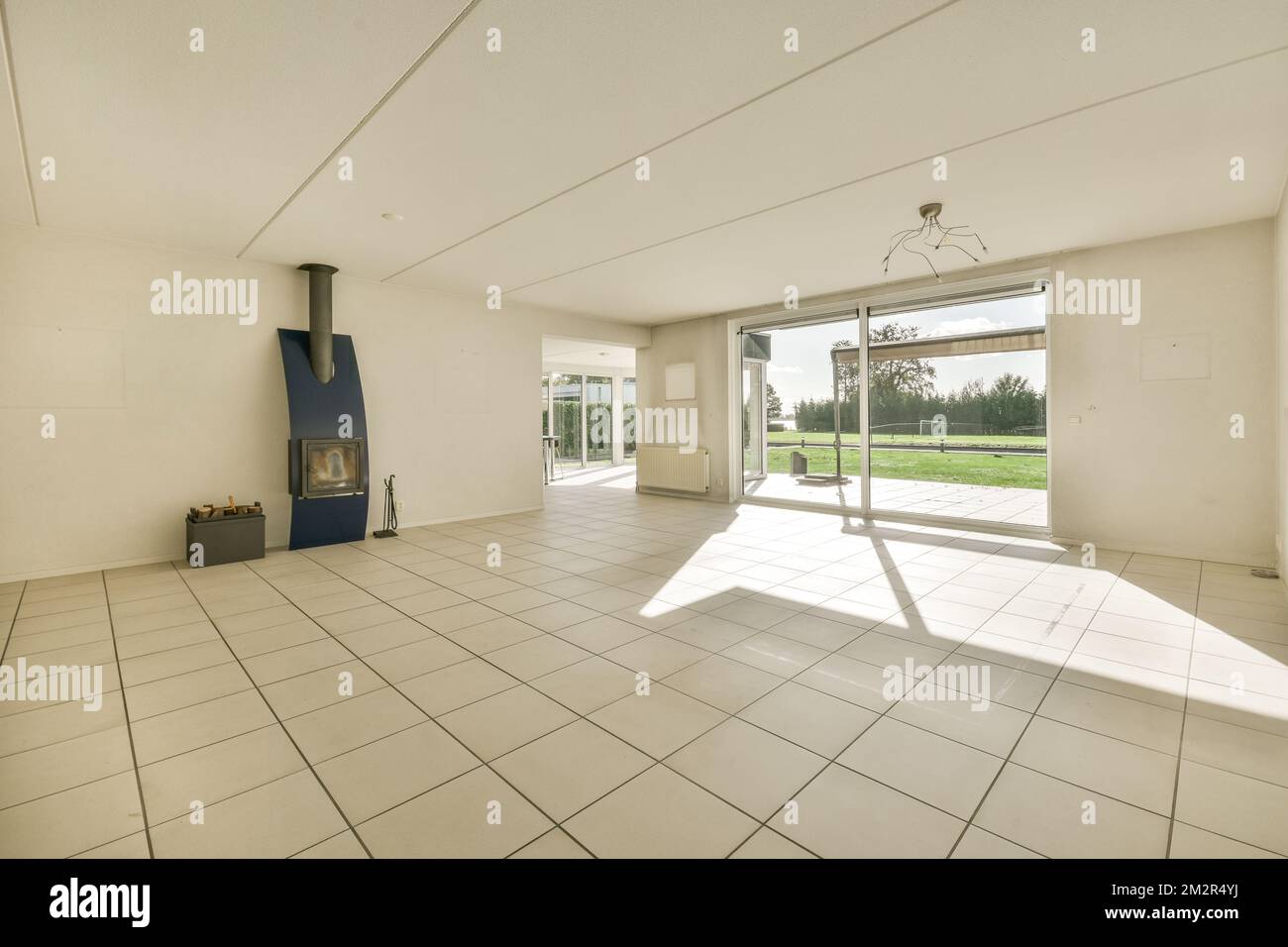 an empty living room with white tile flooring and large sliding glass ...