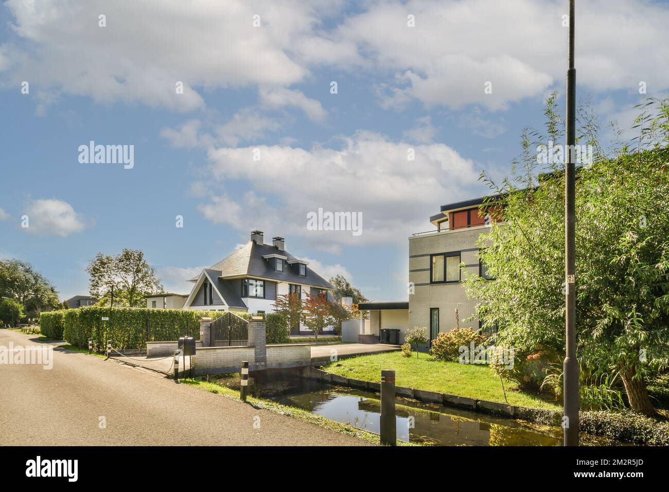 a house on the side of a road with water running through it and trees ...
