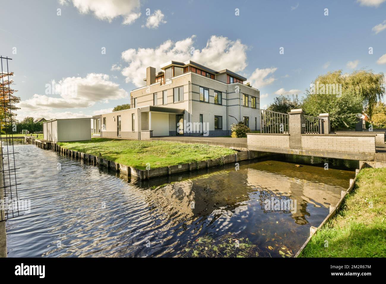 a house on the water's edge, with a bridge in the fore - image is taken ...