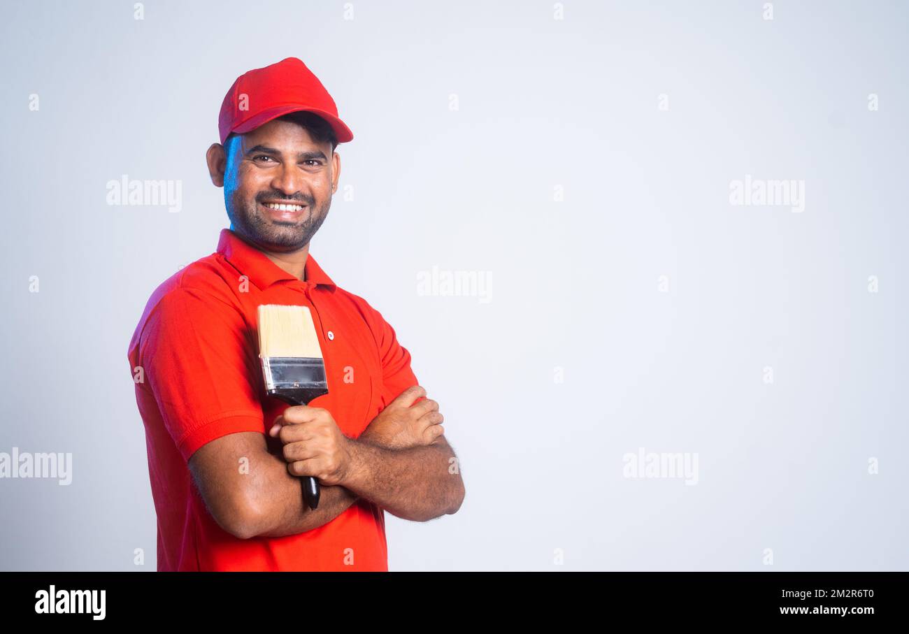 Confident painter standing with crossed arms by holding paint brush ...