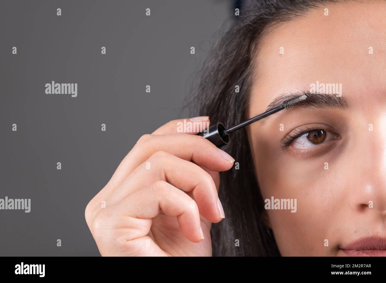 Close up image of brown haired brunette woman shaping eyebrow. Using ...