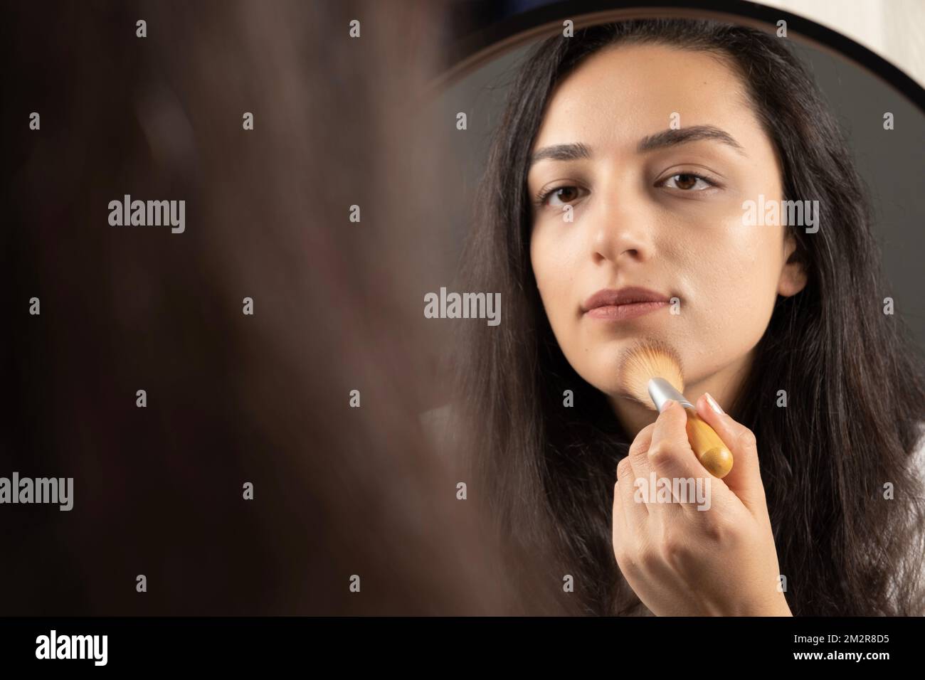 Woman applying makeup. Holding and using brush for powder, blush or ...