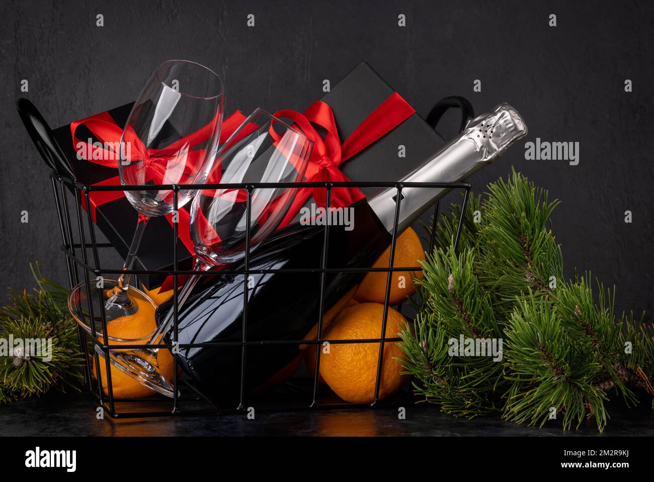 Basket with Christmas gift boxes, champagne, oranges and decor Stock ...