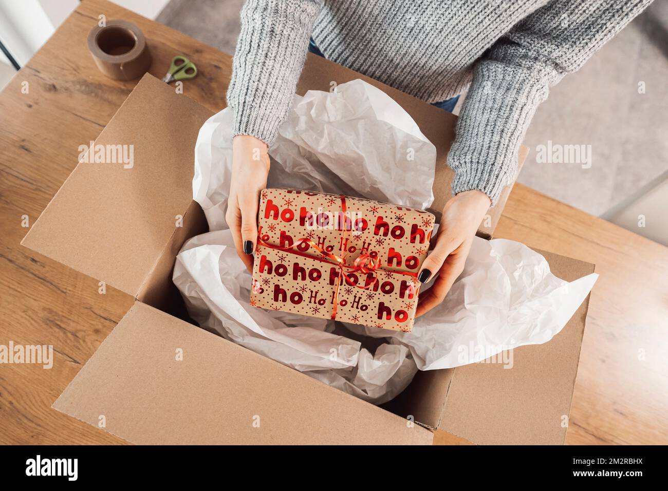 Top down view woman hands holding a Christmas present, putting it ...