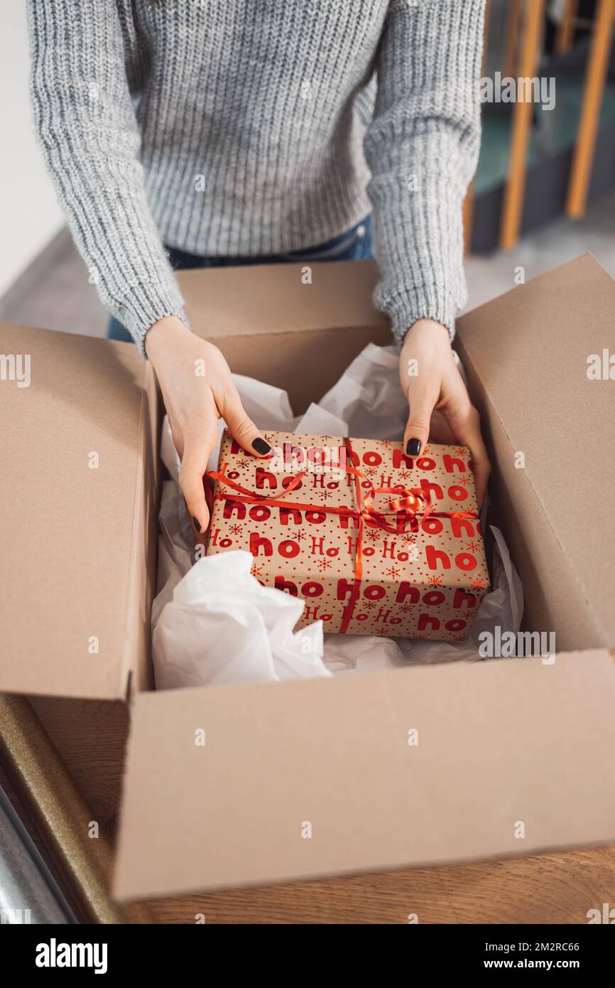 Unrecognizable woman packaging a Christmas present to send in the mail ...