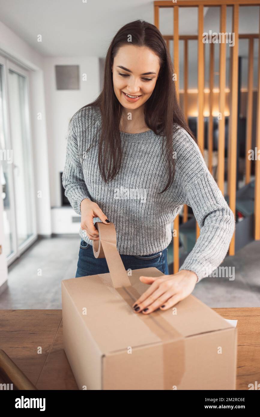 Vertical photo of young woman sending Christmas presents to family ...