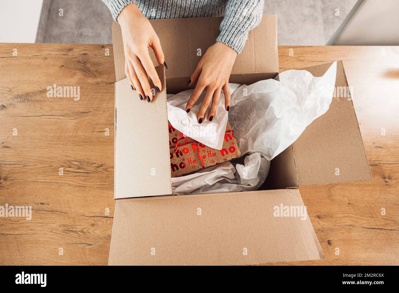Unrecognizable woman, top down view packaging a Christmas present in a ...