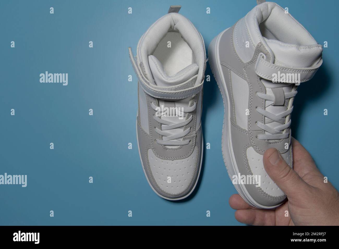 Tactile inspection of new shoes. White sneakers on a blue background ...