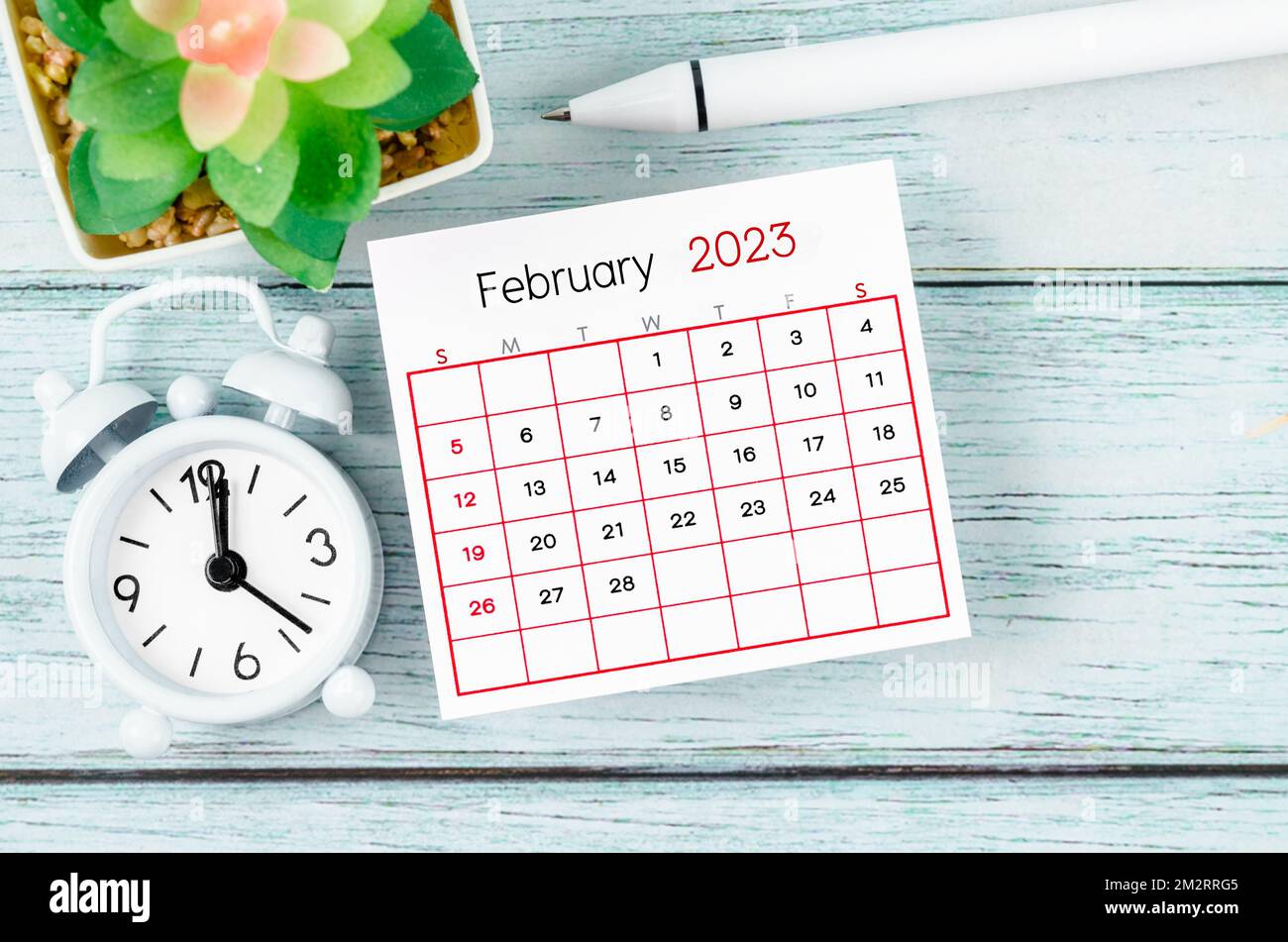 February 2023 Monthly calendar year and alarm clock with pen on blue ...