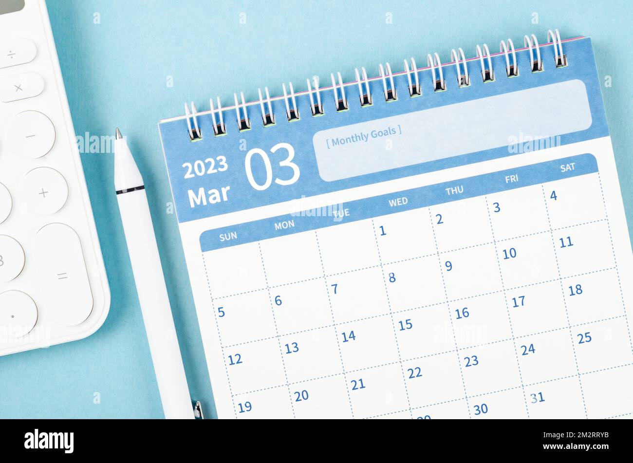 March 2023 desk calendar for 2023 year with calculator and pen on blue ...