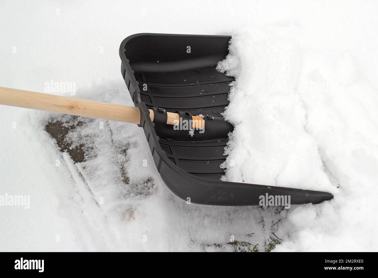 Snow shovel moving snow from a path in the winter Stock Photo - Alamy