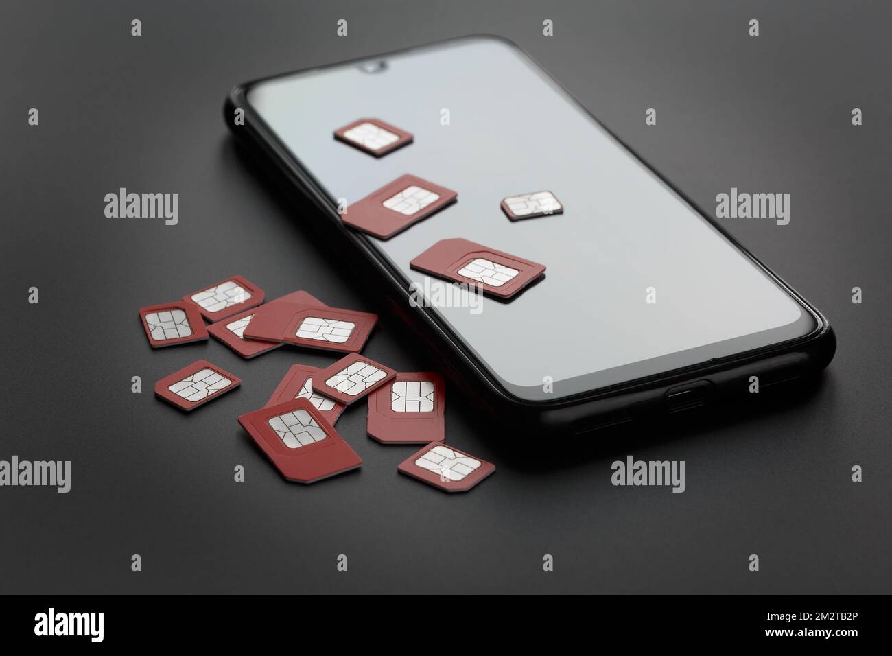 Smartphone and a lot of red sim cards on a gray background, in a dark ...