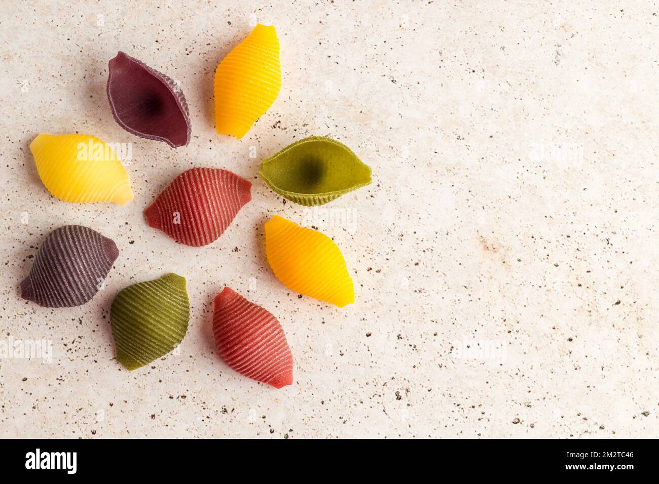 Five colors pasta shells on white stone background. Pasta with turmeric ...