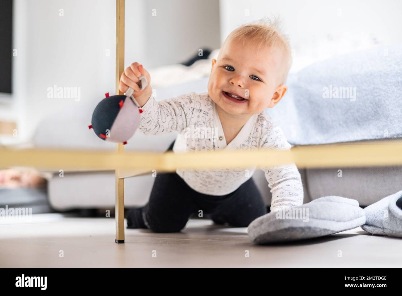 Cute infant baby boy playing with hanging ball, crawling and standing ...
