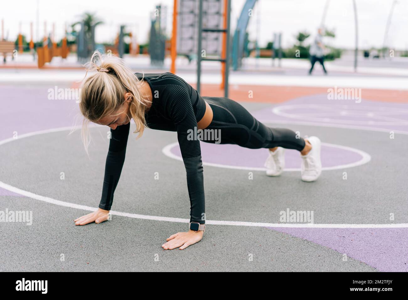 A woman athlete stands in a plank on the sports ground during a workout ...