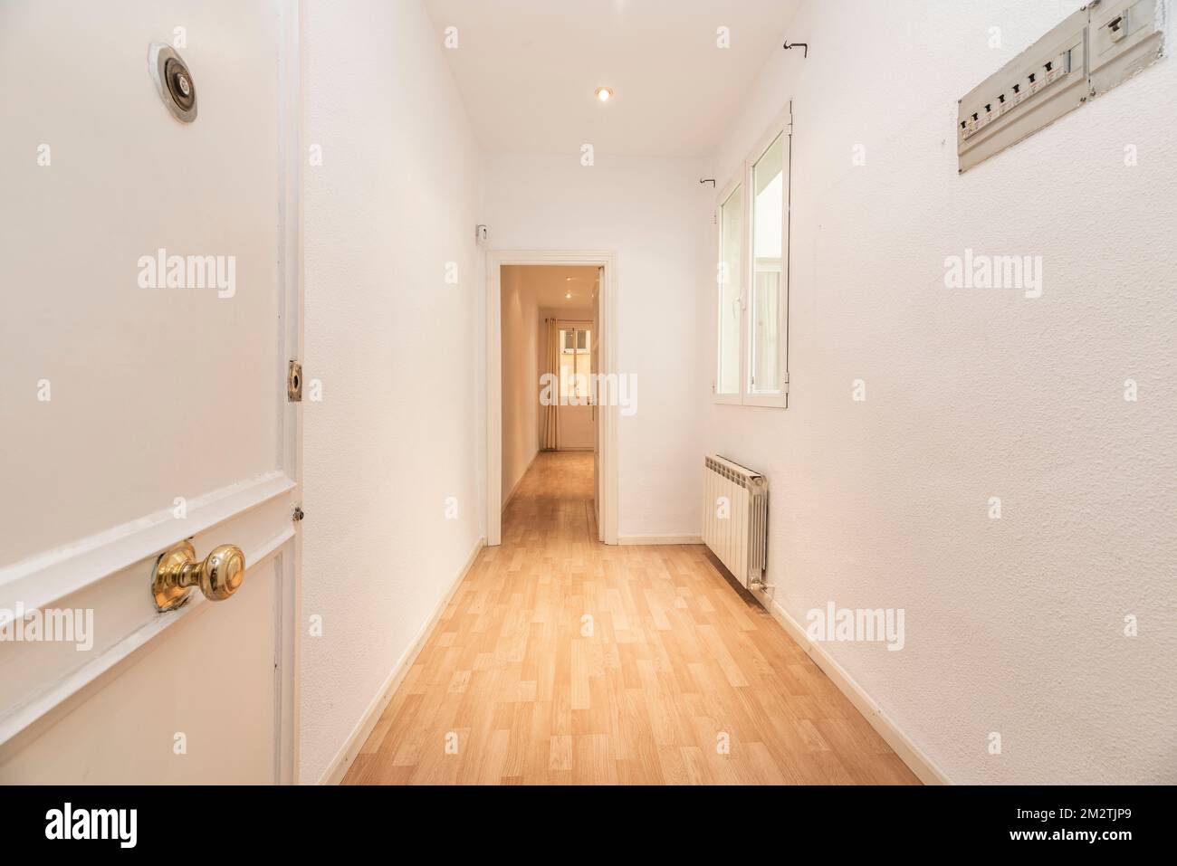 hallway of a house with all the walls painted plain white, a fuse box ...