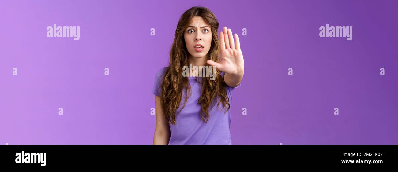 Worried shocked curly-haired woman gasping stare camera anxiously pull ...