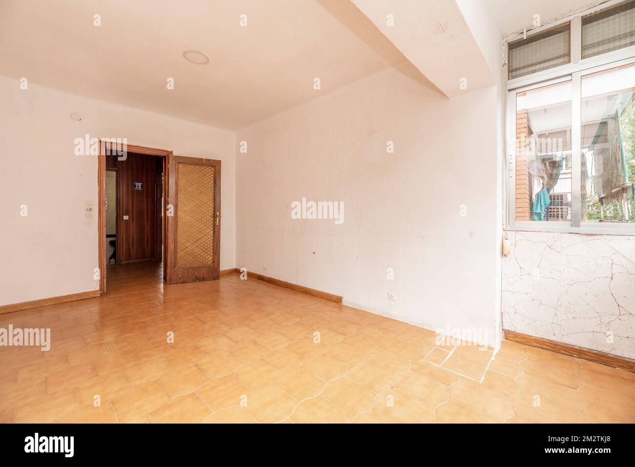 An old and used empty room with tiled floors and enclosed terrace ...