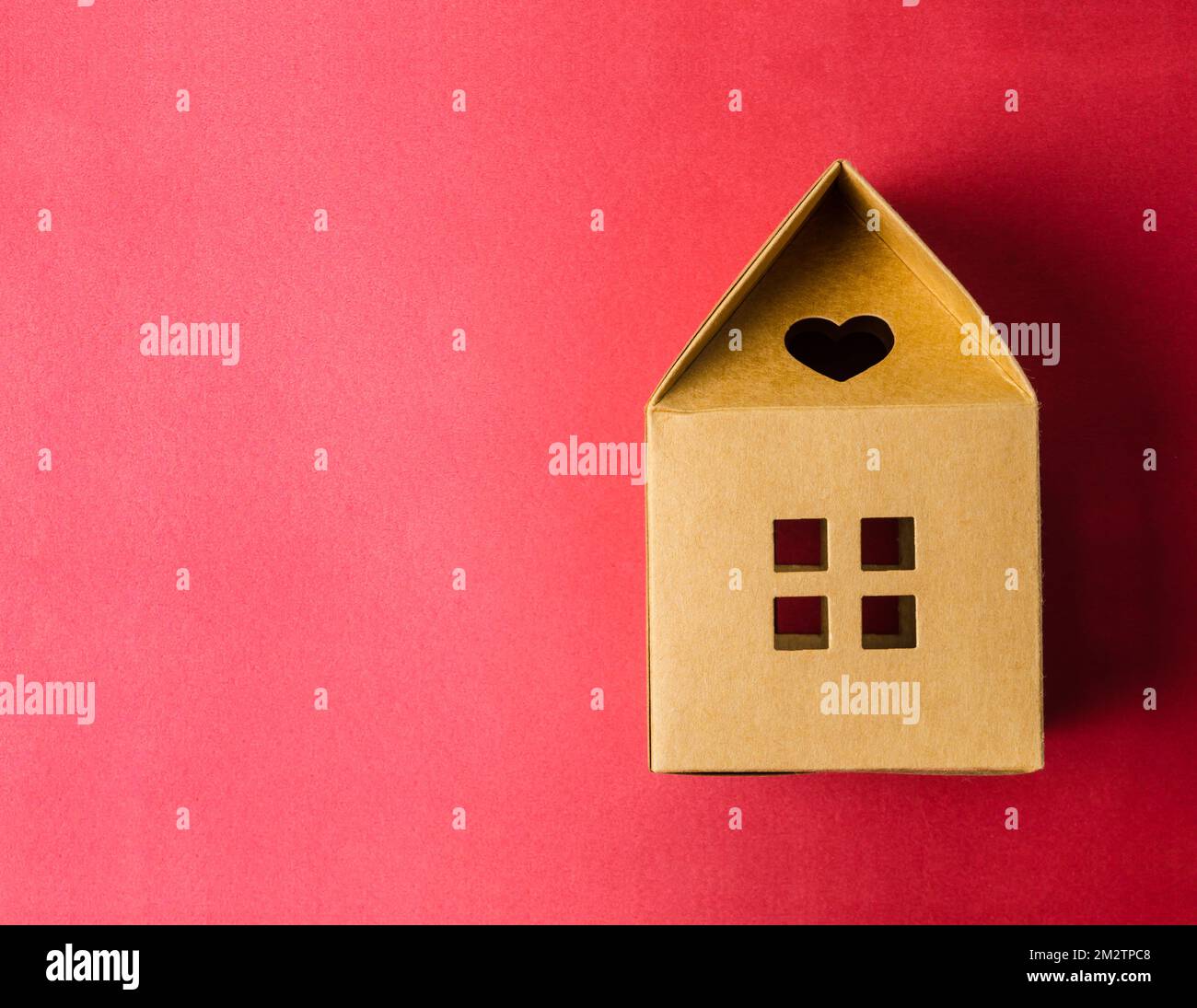 Brown paper house origami on red background with empty space for your ...
