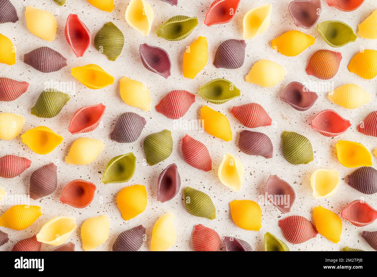 Top view of five colors pasta shells on white stone background ...