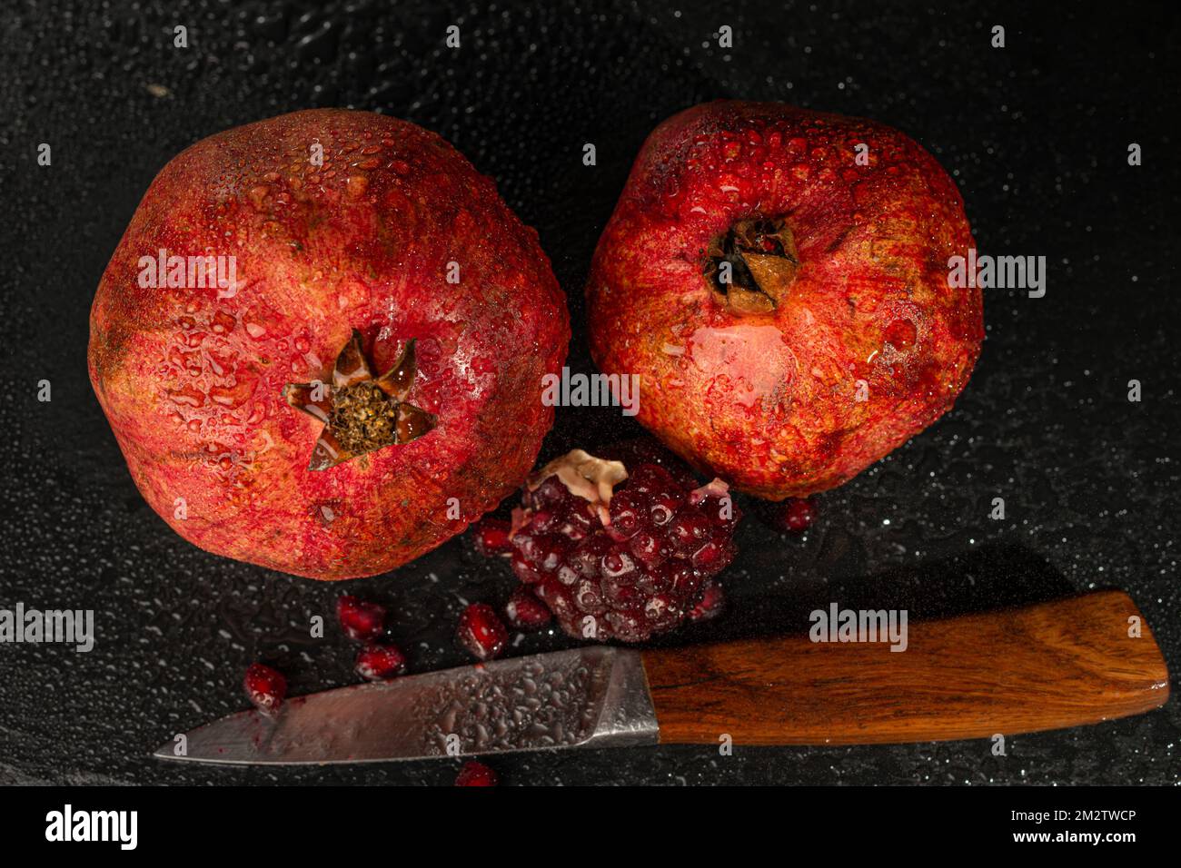 red ripe wet pomegranate on a black stone board Stock Photo - Alamy