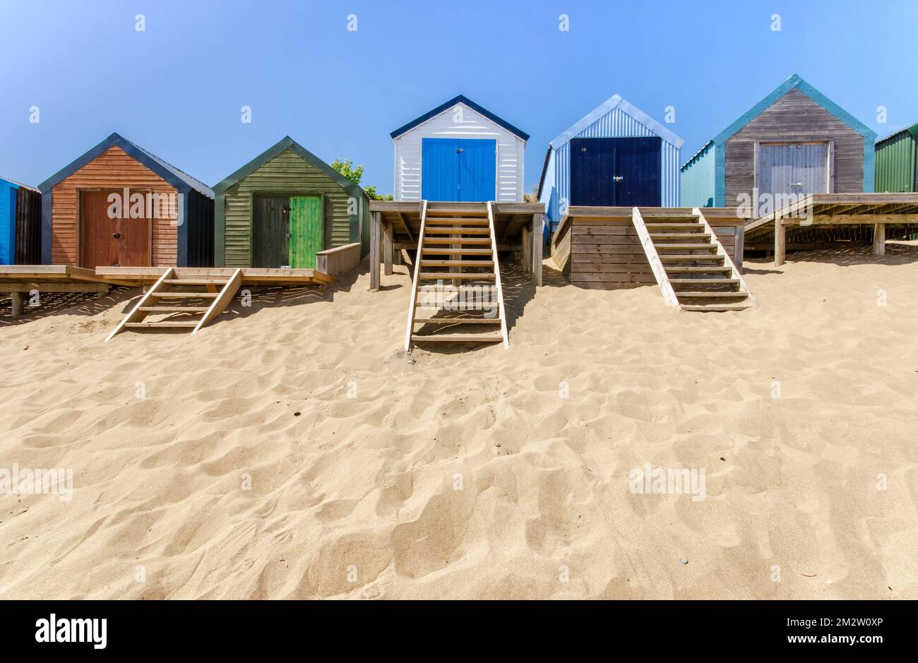 A line of beach huts on a sandy beach Stock Photo - Alamy