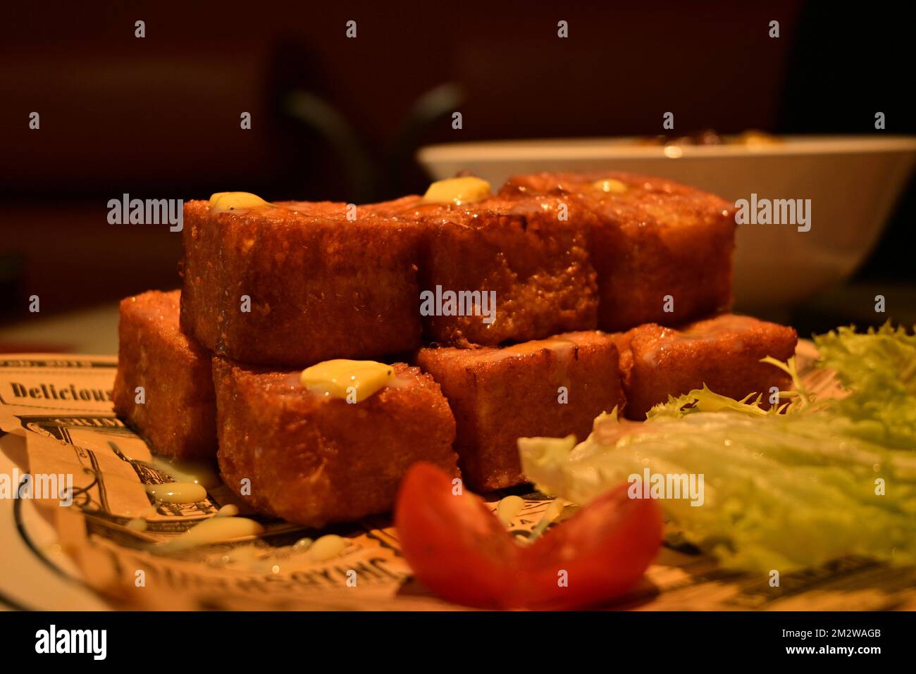 A closeup shot of French toast cubes, a piece of lettuce and tomatoes ...