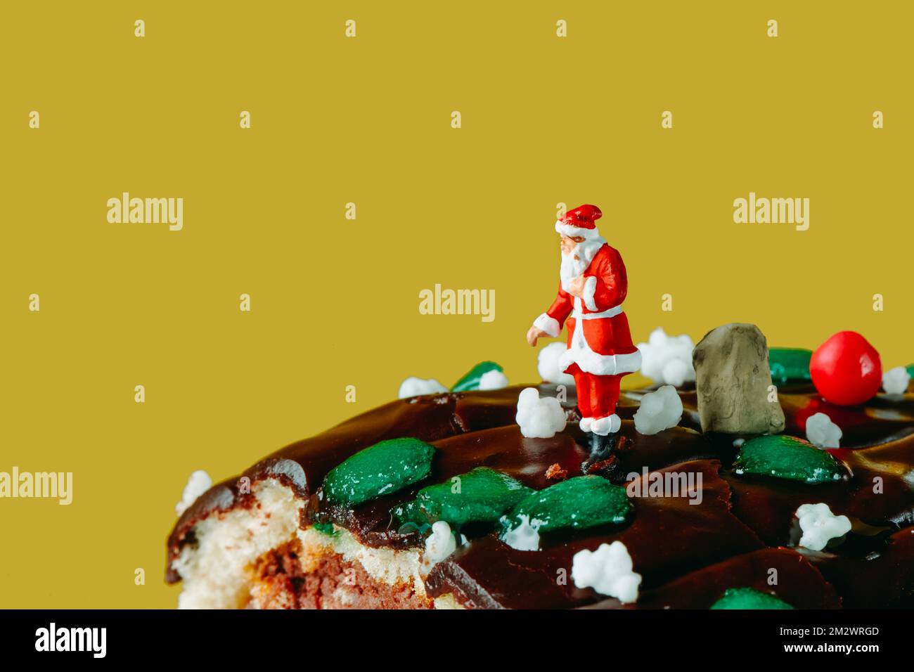 a miniature santa claus stands next to a sack with gifts, on a yule log ...