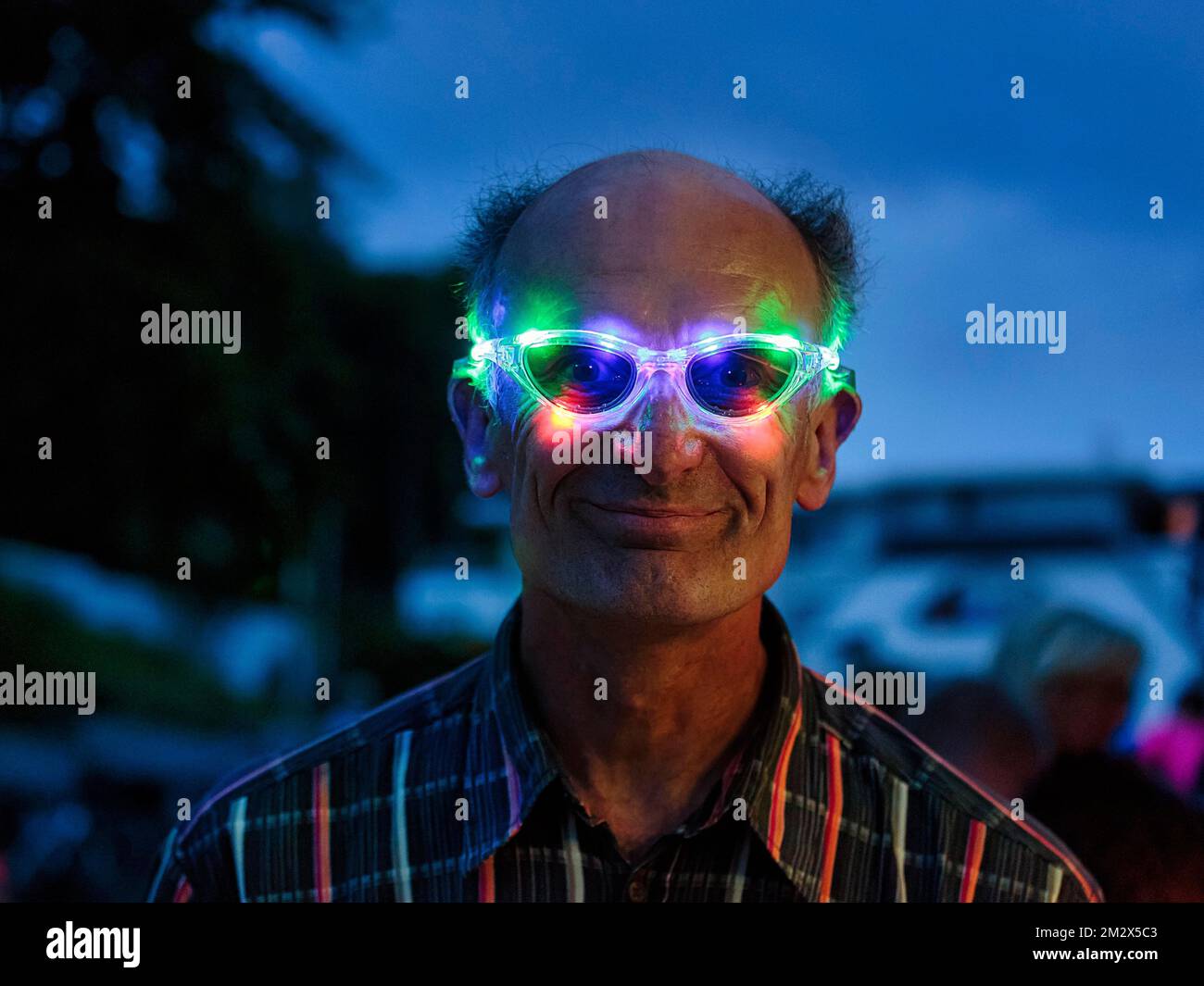 Funny portrait with colourful LED glasses at dusk, eye-catching ...