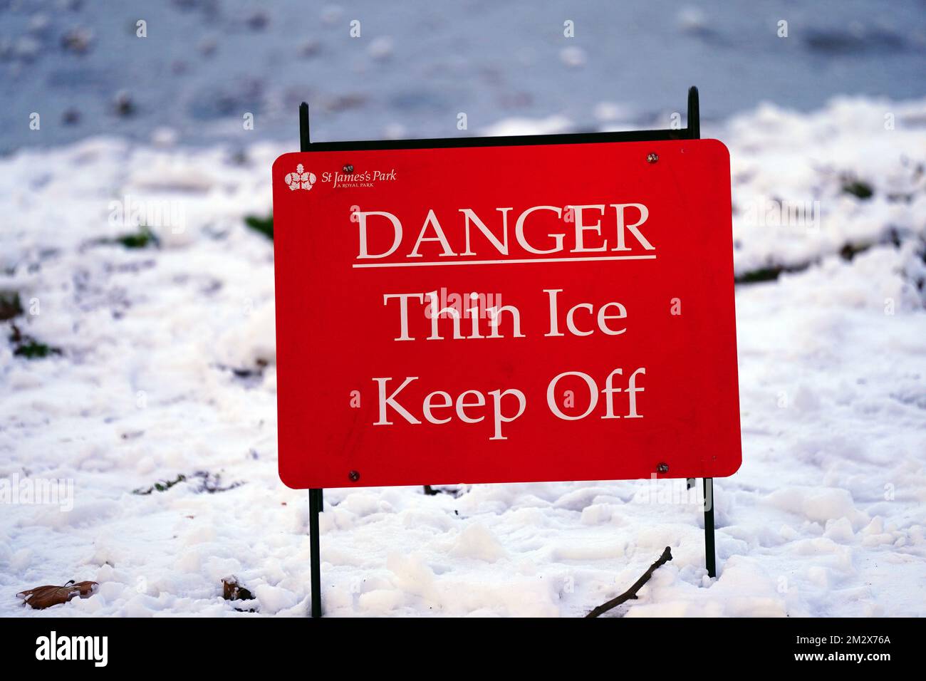 Sign warning of thin ice by the lake in St James's Park, London. Snow ...