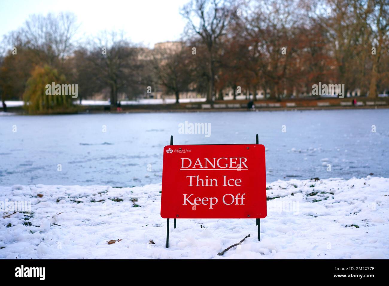Sign warning of thin ice by the lake in St James's Park, London. Snow ...