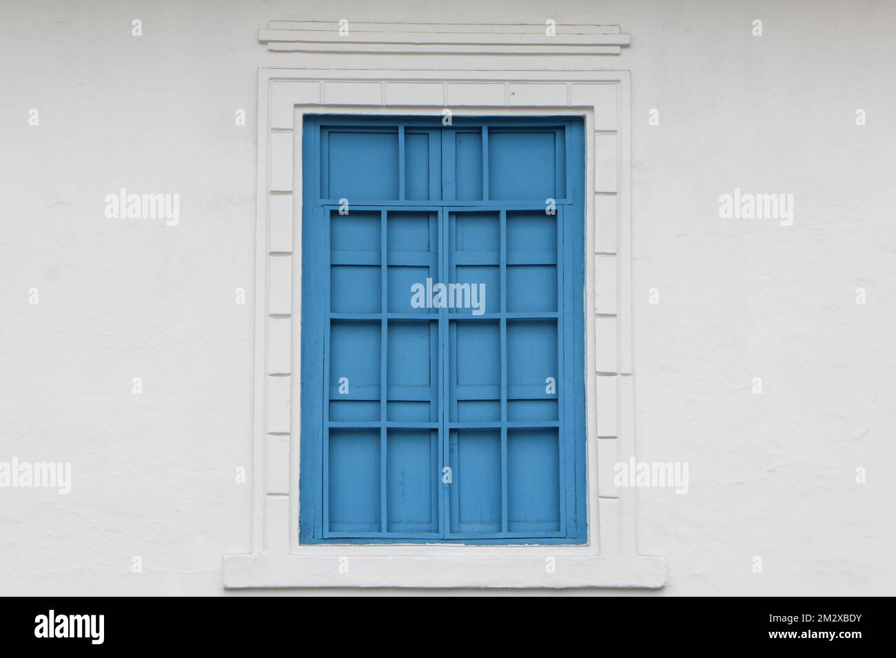 A closeup of the vintage blue window with bars and a white patterned ...