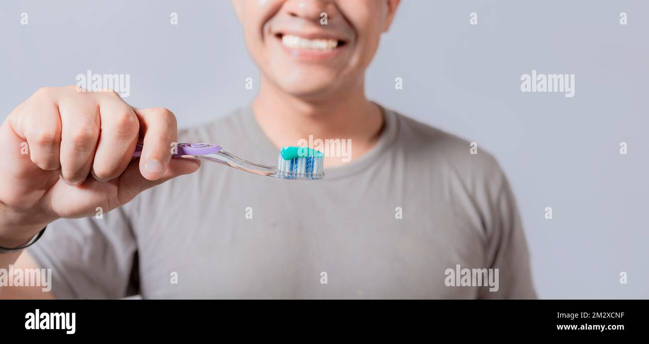 Young man showing toothbrush with toothpaste isolated, guy holding ...