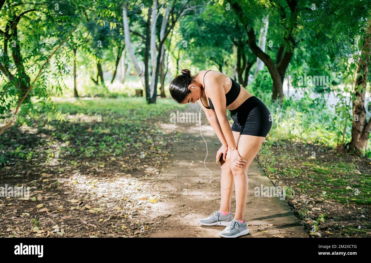 Sporty young woman tired from running. A sporty girl taking a break after running. Concept of ...