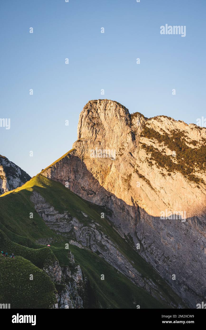 A vertical shot of a rock formation on a mountain against a blue sky ...