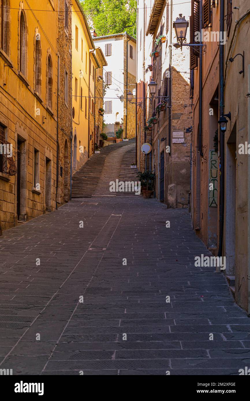 Narrow alley with pastel-coloured house facades, Massa Marittima ...