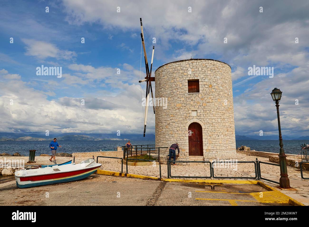 Restored windmill, boat, blue sky, grey-white cloudCorfu Town, Corfu ...
