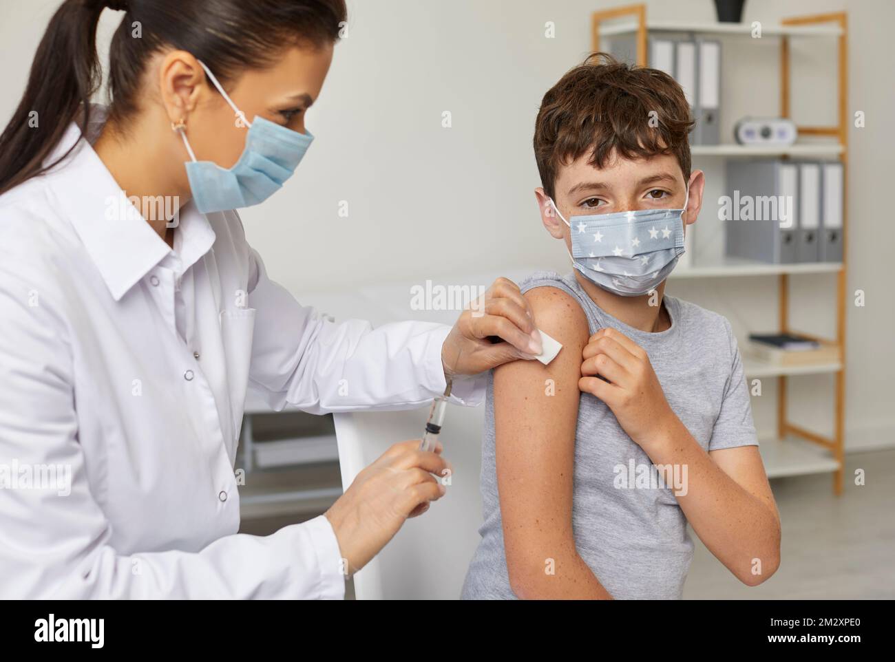 Nurse or doctor giving injection to little school boy to protect him ...