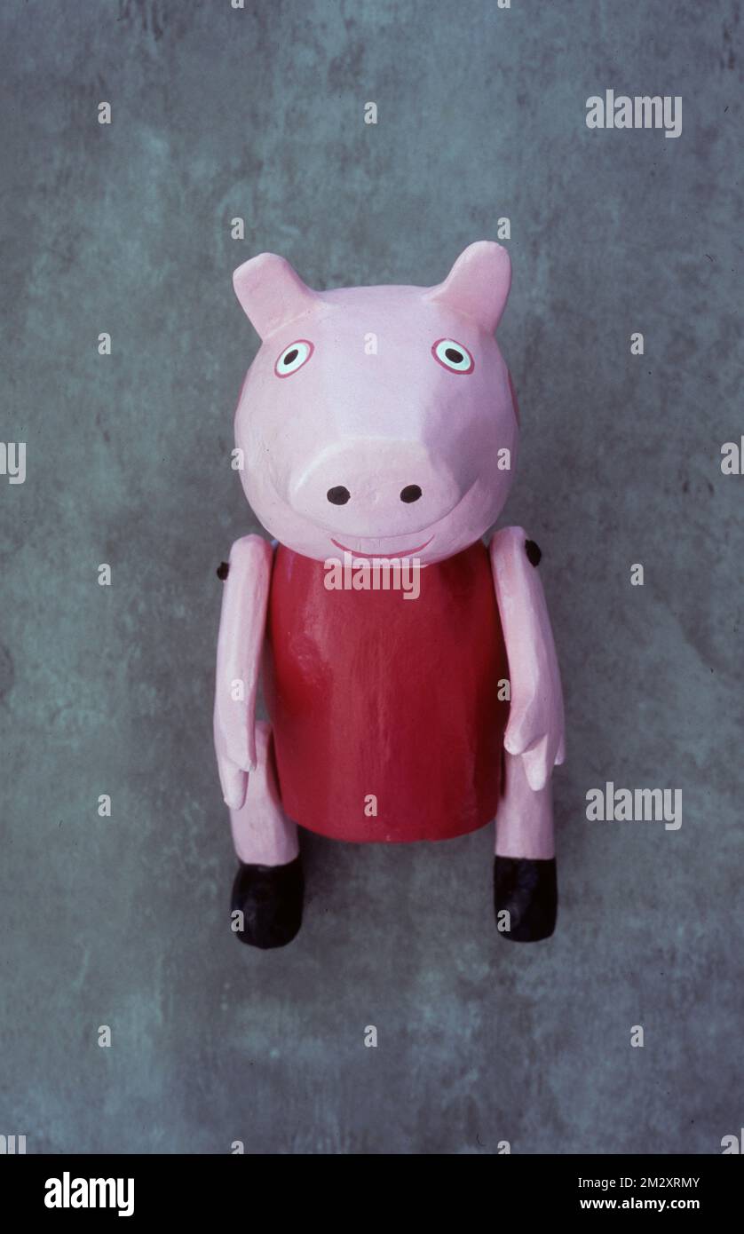 Naive sculpted woooden model of pink pig with red body and moging legs ...
