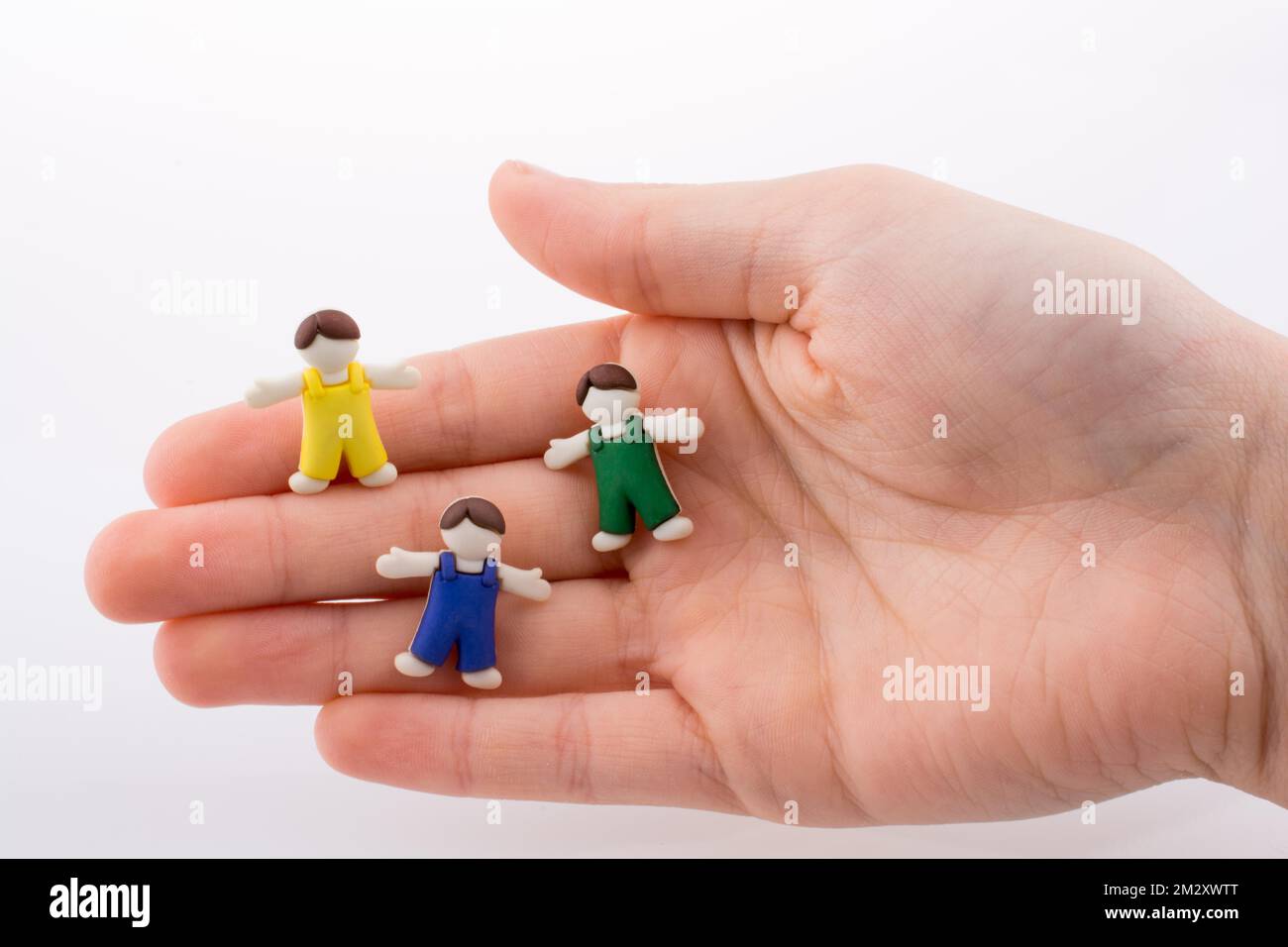 Hand holding colorful dressed children figures on a white background ...