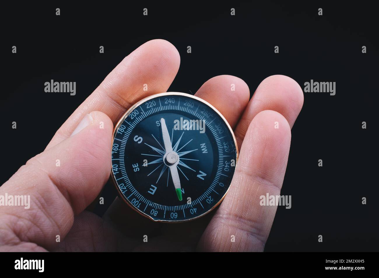 Child hand holding a compass on a black background Stock Photo - Alamy