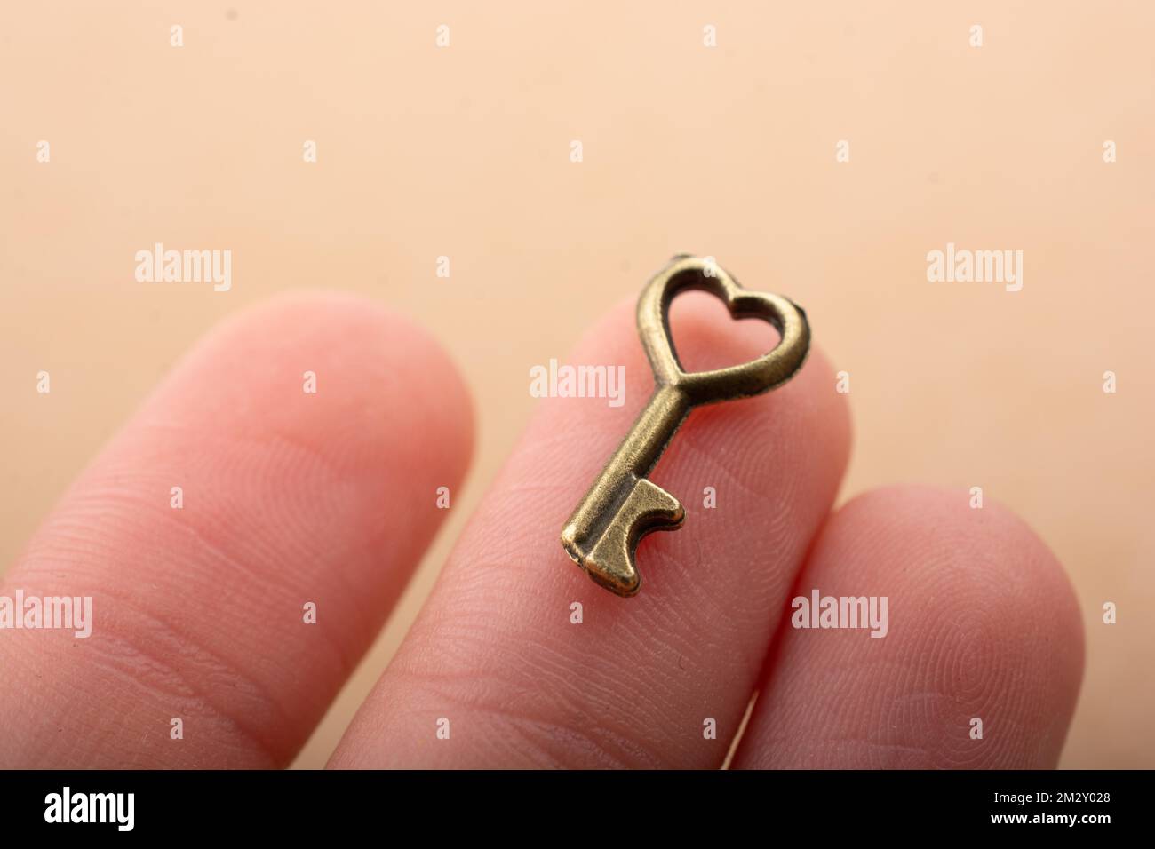 Tiny key with heart shape placed on the finger tip Stock Photo - Alamy