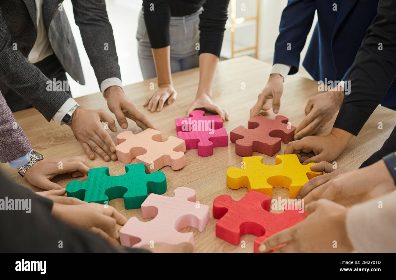 Team of young business people connecting colorful parts of jigsaw ...