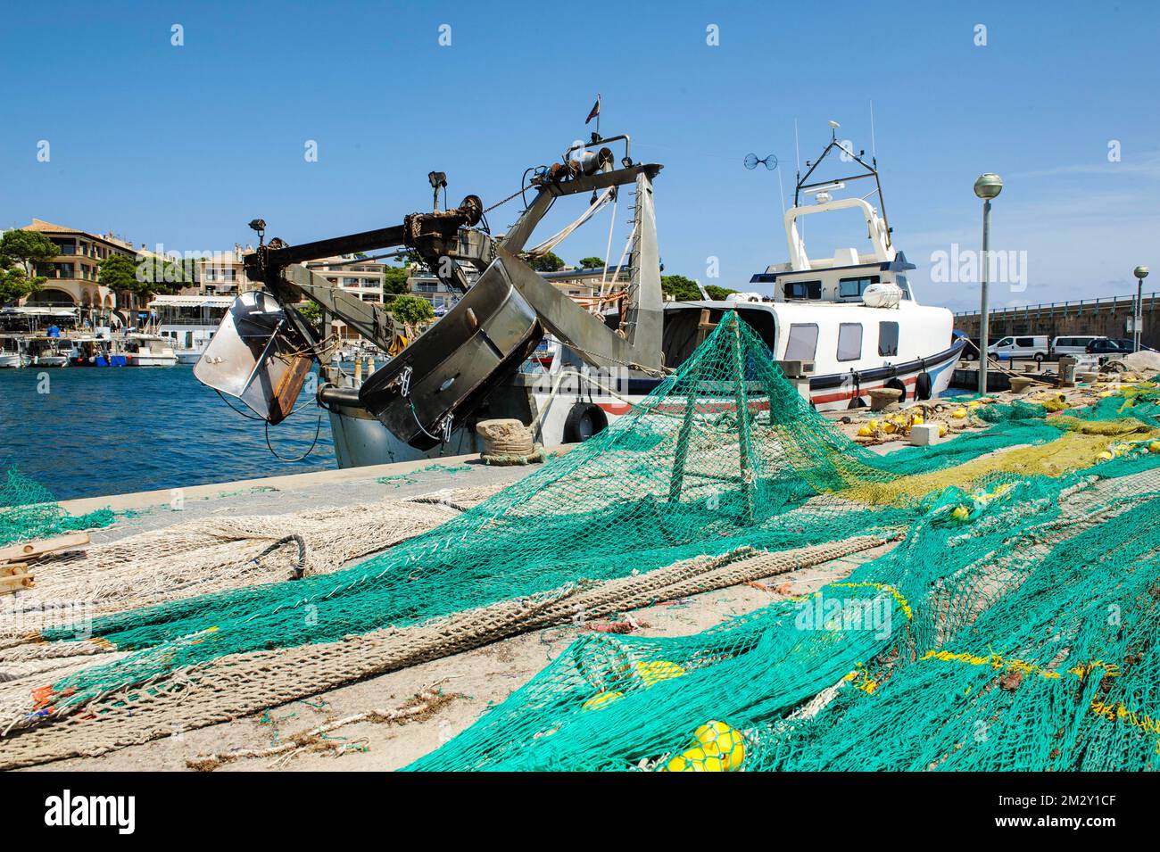 Fishing nets lying stretched out to dry for repair on quay at harbour ...