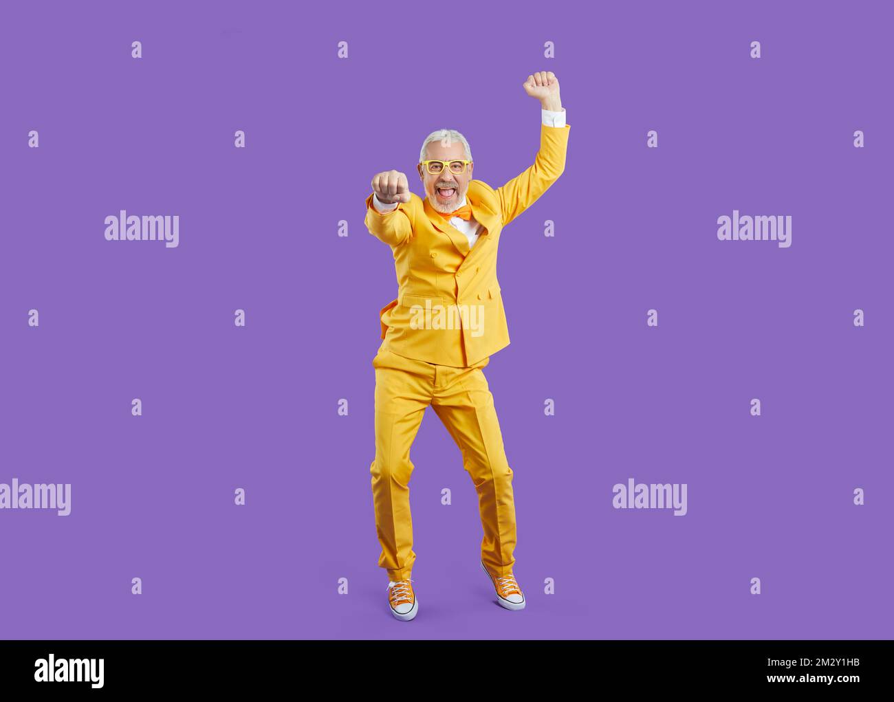 Funny senior man in yellow party suit dancing and having fun against ...